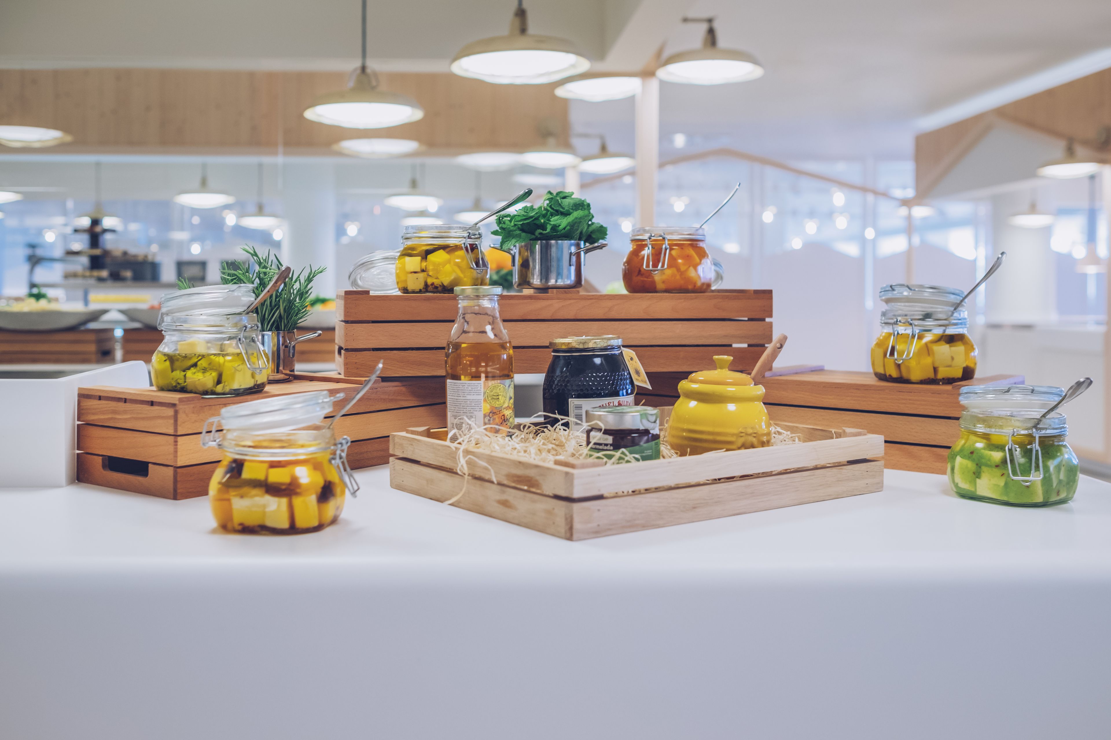 Disposição de buffet com diversos alimentos e acompanhamentos expostos em caixas de madeira e mesas.