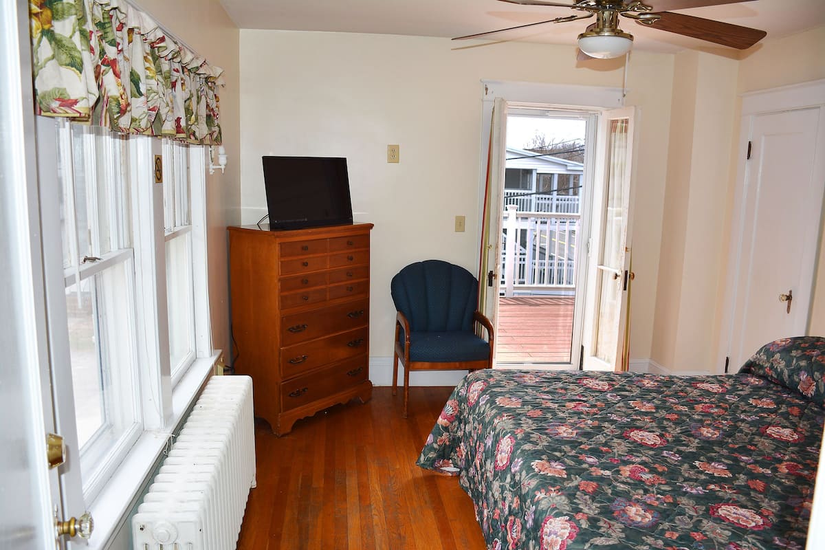 Quarto com cama, cômoda, cadeira e radiador.