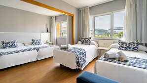 Quarto de hotel com duas camas, uma mesa e uma janela com vista para a cidade.