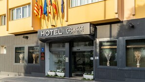 Um hotel com fachada moderna, várias bandeiras e uma placa indicando que é um hotel.