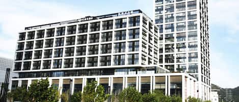 Um hotel moderno com vários andares, destacando um edifício central imponente e uma construção mais alta à direita.