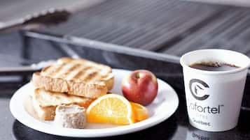 Um prato com torradas, uma maçã e uma fatia de laranja, e uma xícara de café com o logotipo de um hotel.