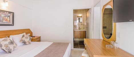 Quarto com cama, mesa de cabeceira e cômoda de madeira com espelho.