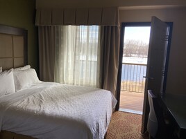 Quarto com cama, televisão e vista para uma varanda.