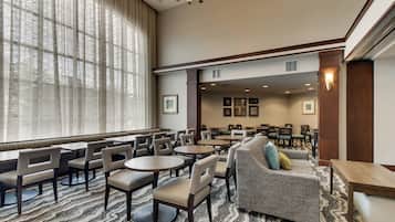 Um hall de hotel com uma janela ampla, área de estar e um candelabro.