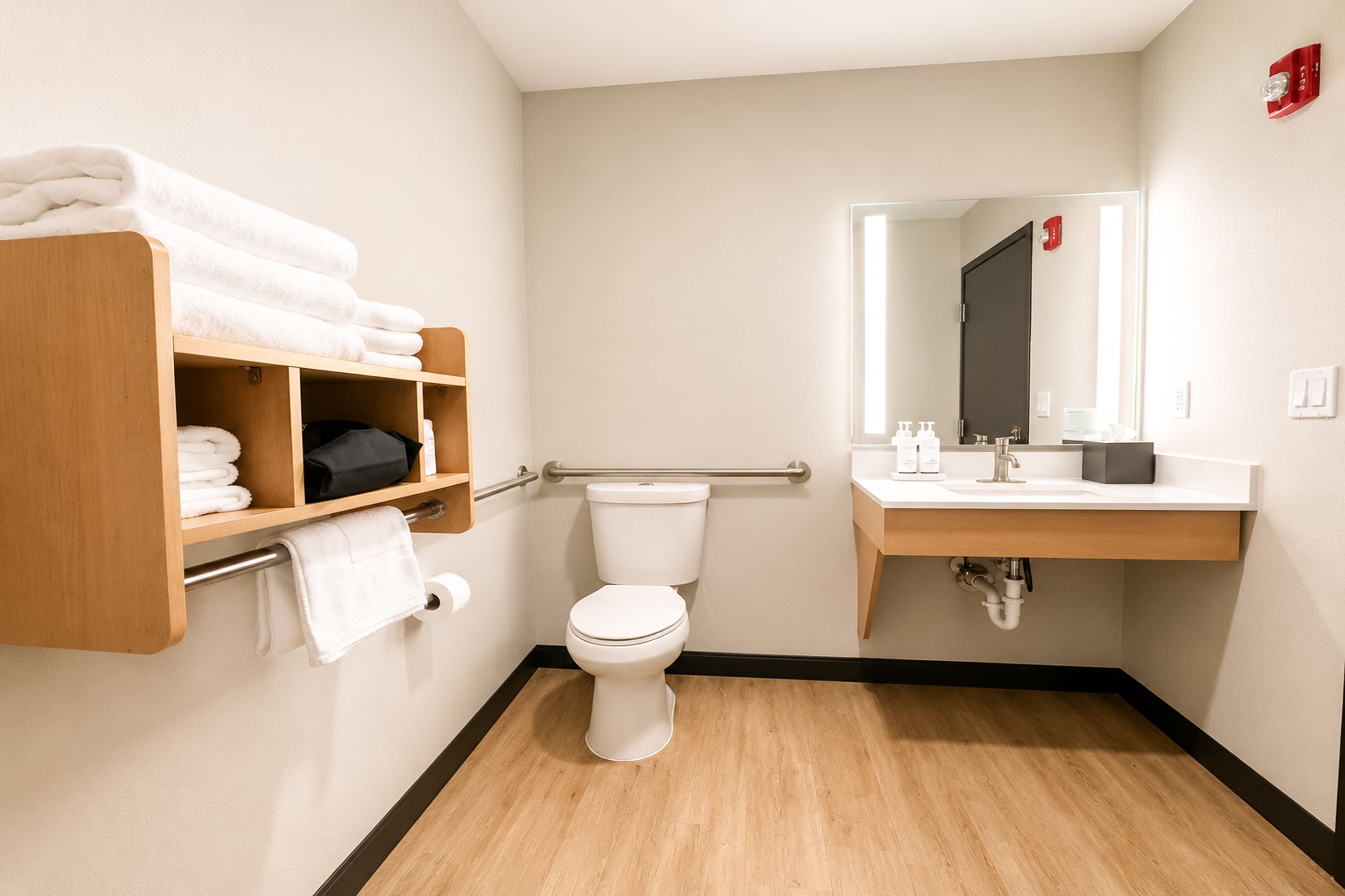 Uma casa de banho de hotel com sanita, lavatório, espelho e porta-toalhas.
