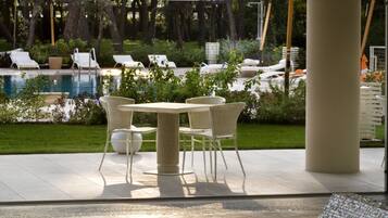 Área de piscina com espreguiçadeiras, guarda-sóis e uma mesa com cadeiras.