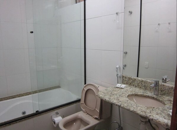 Casa de banho com cabine de duche em vidro, sanita e lavatório com bancada em granito.