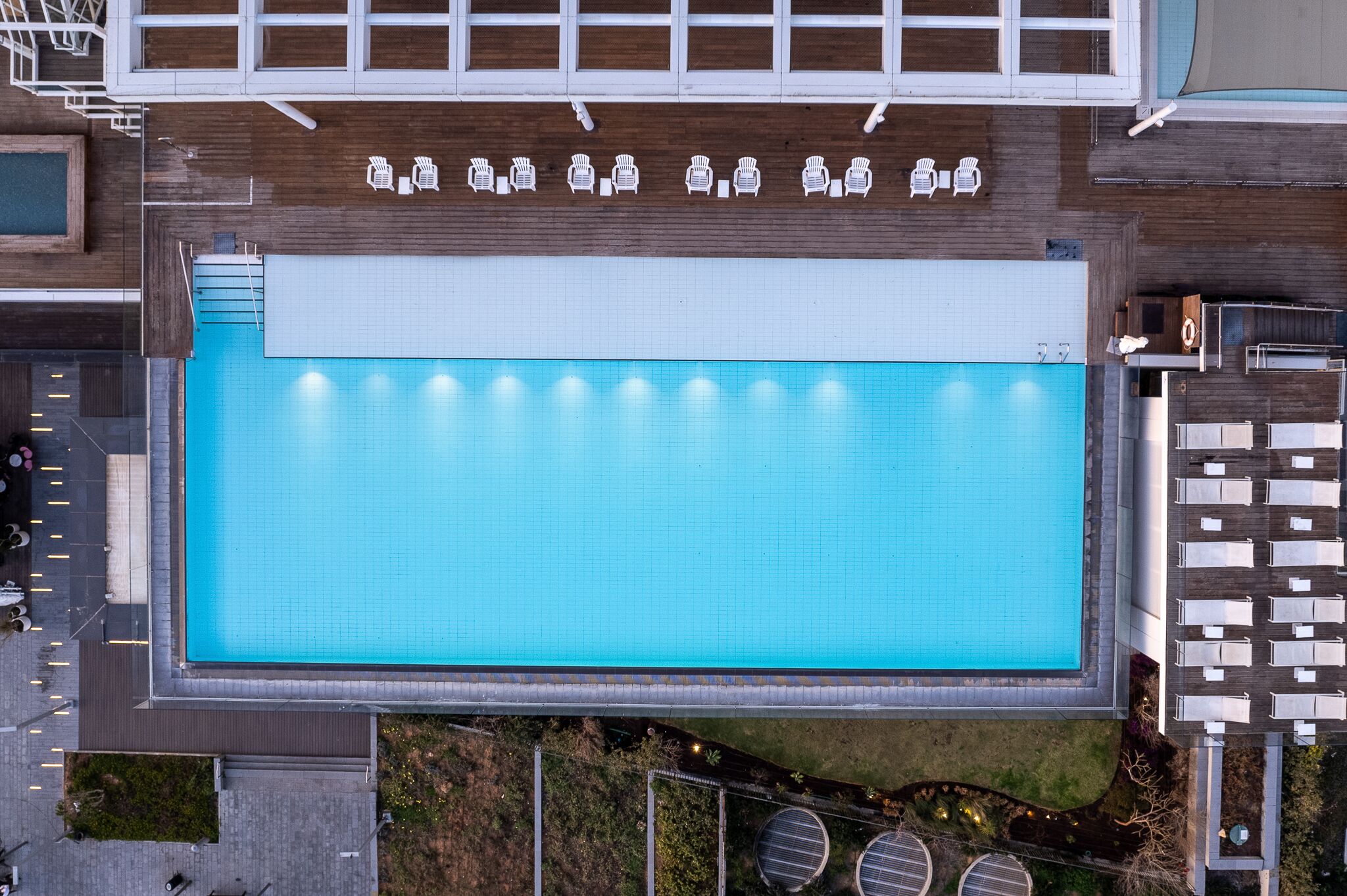 Vista aérea de uma piscina com espreguiçadeiras e uma área coberta.