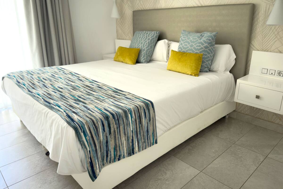 Uma cama bem arrumada com um edredom listrado, dois travesseiros e uma mesa de cabeceira com abajur.