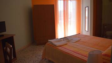 Quarto com uma cama, um guarda-roupa de madeira, uma escrivaninha com cadeira e uma janela com cortinas.
