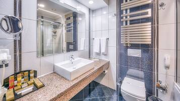 Uma casa de banho moderna com uma sanita, um lavatório branco e um chuveiro com cabine de vidro.