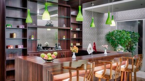 Uma cozinha moderna com uma ilha de madeira, banquetas e luminárias pendentes verdes.