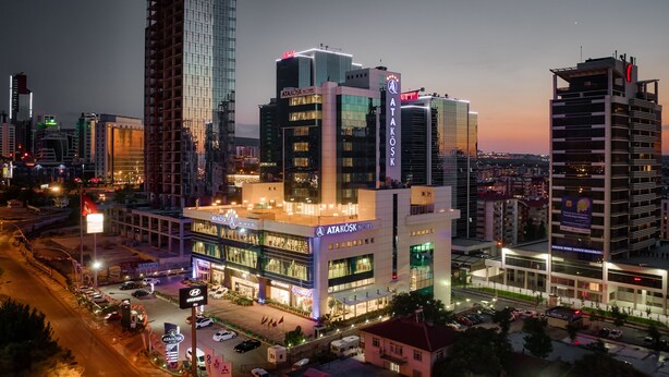 Um hotel moderno com vários andares, uma placa chamativa e uma fachada bem iluminada.