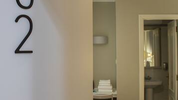 Quarto de hotel com uma cama, banheiro com pia e porta-toalhas.