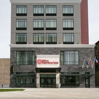 Um hotel Hilton Garden Inn com fachada moderna, janelas amplas e uma placa bem visível.
