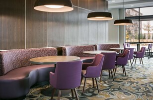 Um restaurante moderno com assentos acolchoados, mesas redondas e iluminação pendente.