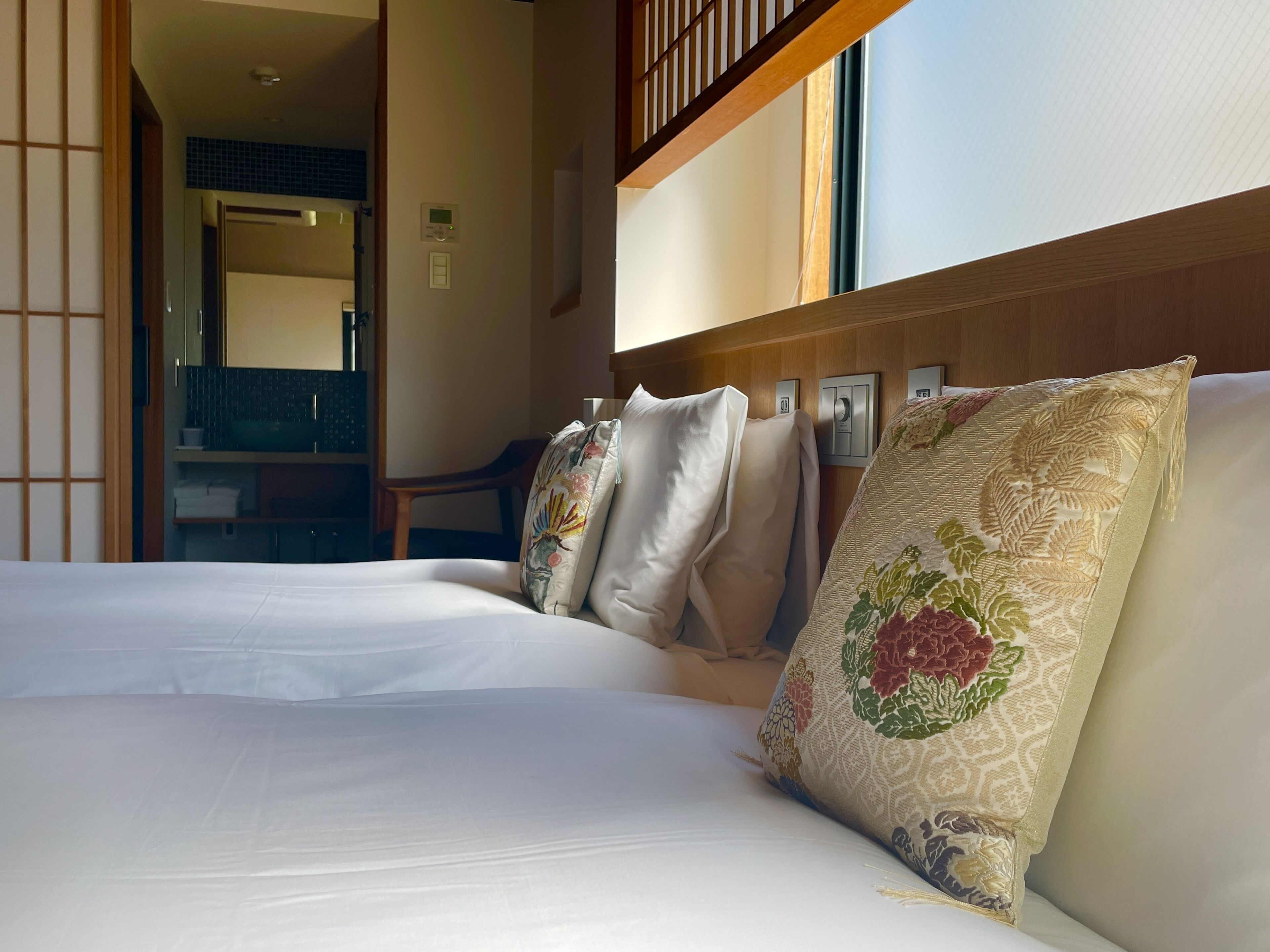 Quarto de hotel com cama, almofadas, janela e vista para o exterior.