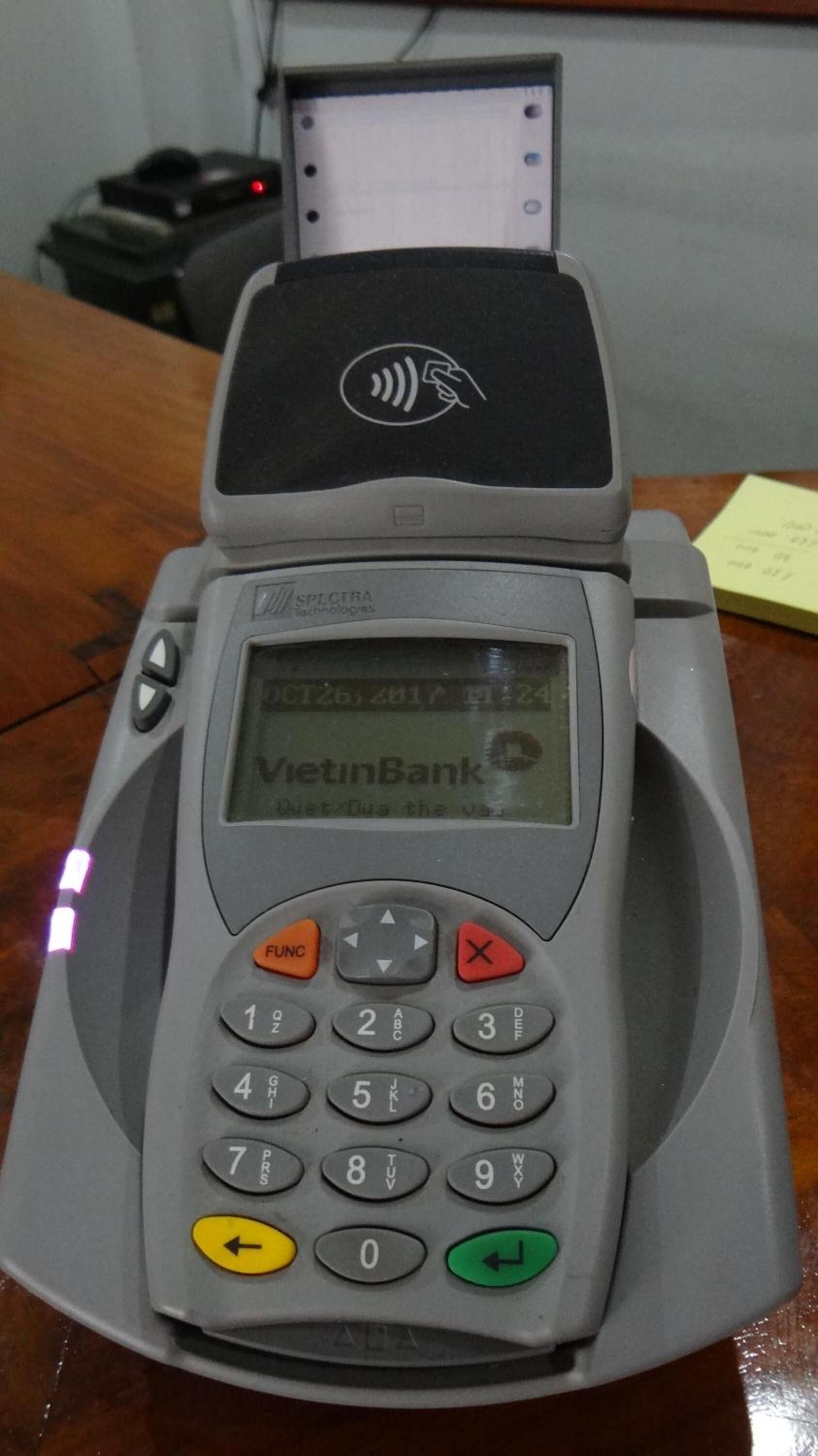 Um terminal de pagamento com tela exibindo "VetinBank" e um teclado com diversos botões.