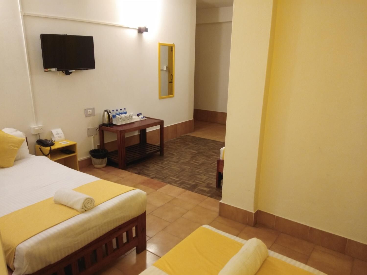 Quarto de hotel com duas camas, televisão, uma mesinha com artigos de higiene e um espelho.