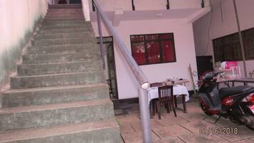 Uma escadaria leva a um quarto com uma mesa e cadeiras, e uma scooter estacionada do lado de fora.