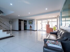 Um lobby moderno com balcão de recepção, escada e área de espera com sofá de couro.