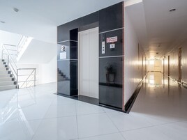 Um saguão de hotel moderno com escada, aviso 'Não Fumar' e piso limpo e refletor.