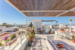 Terraço no terraço com área de estar externa, plantas em vasos e vista para o mar.