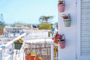 Uma varanda com vasos de plantas e vista para o mar.