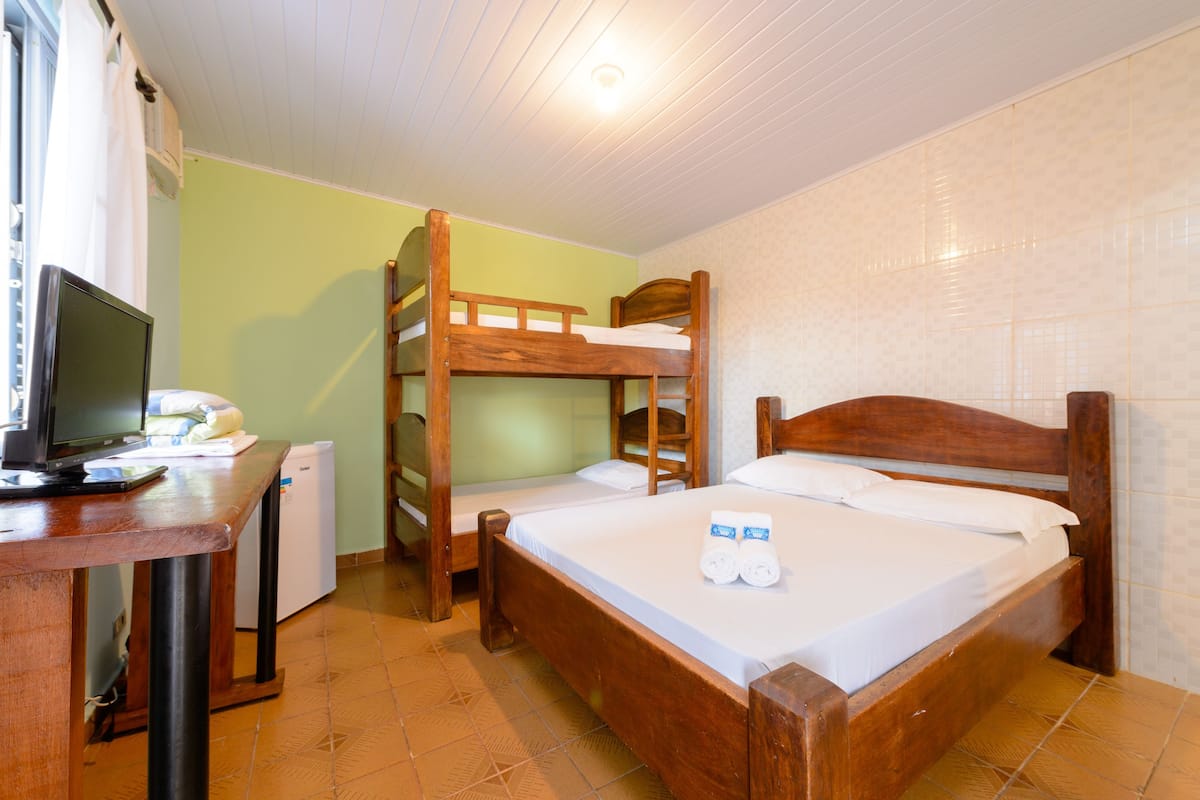 Um quarto com beliches, uma escrivaninha com computador e uma pequena geladeira.