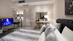 Uma sala de estar moderna com televisão, sofá, escrivaninha e espelho.