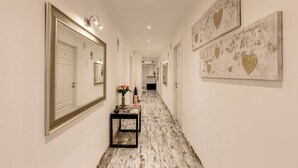 Um corredor com piso branco, um espelho e duas obras de arte emolduradas nas paredes.