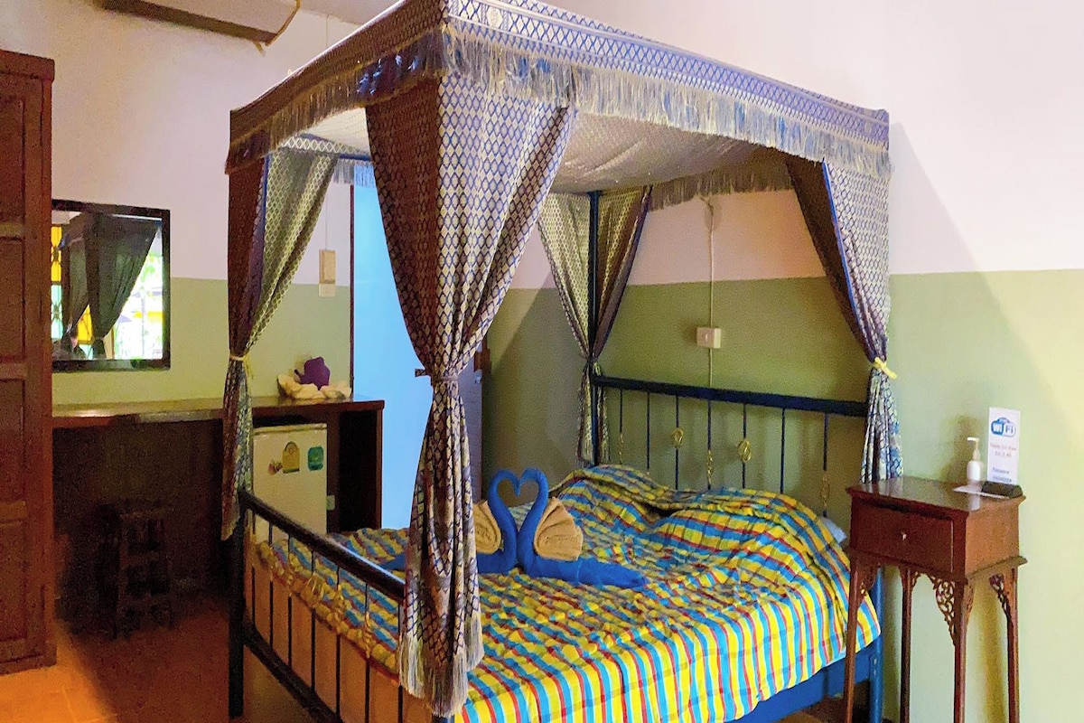 Uma cama de dossel com cortina, uma mesa de cabeceira e um espelho na parede.