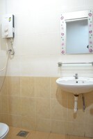 Casa de banho com lavatório branco, espelho com moldura decorativa e chuveiro manual.