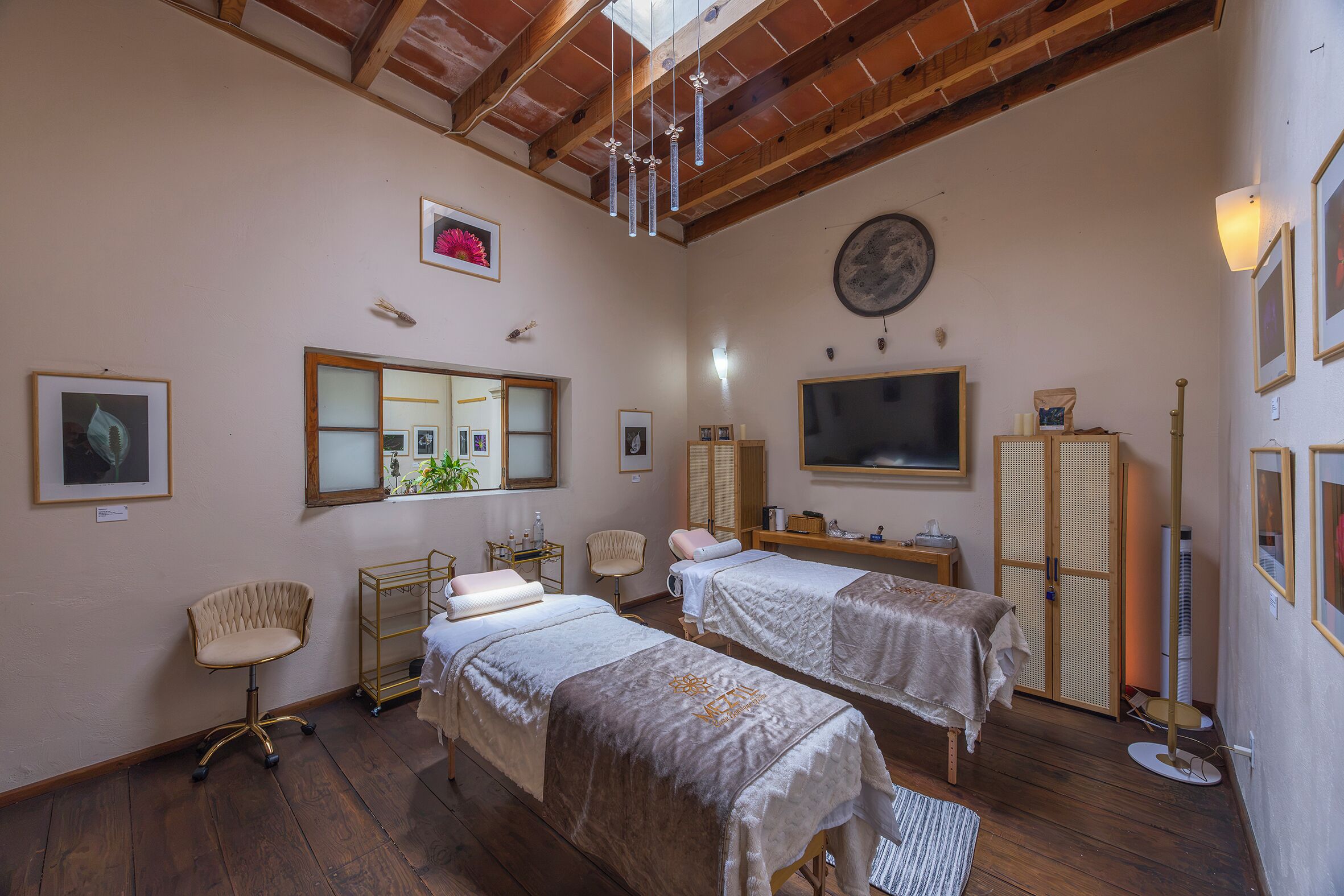 Quarto com duas camas, um espelho, um relógio e uma televisão.