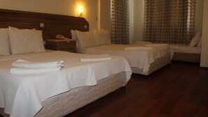Quarto de hotel com duas camas, cabeceira de madeira, mesa de cabeceira com abajur e espelho.