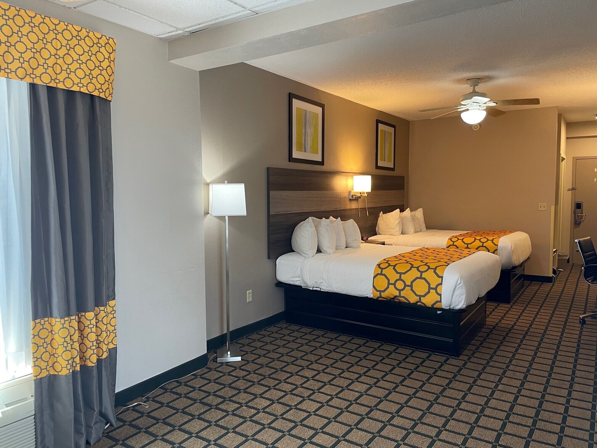 Quarto de hotel com cama grande, luminária de chão e ventilador de teto.
