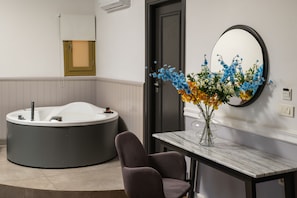 Um banheiro moderno com uma banheira independente, um espelho sobre a pia e um vaso com flores em uma mesa de mármore.