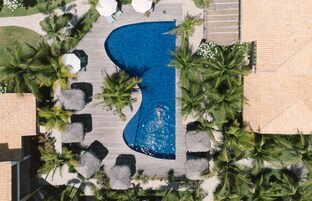 Vista aérea de uma piscina rodeada por palmeiras e espreguiçadeiras.