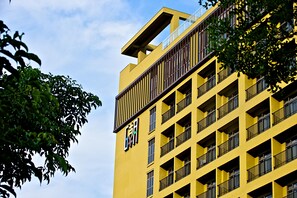 Um edifício amarelo com várias varandas e um logótipo visível na lateral.