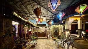Um pátio tradicional com lanternas pendentes decorativas, mobiliário rústico e uma área de recepção.