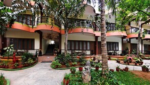 Hotel de vários andares com varandas, plantas em vasos e uma escadaria central.
