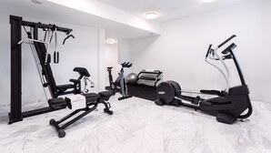 Uma academia moderna em casa com diversos equipamentos de exercício, incluindo esteira, bicicleta ergométrica e banco de musculação.
