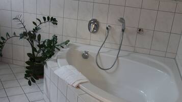 Casa de banho com banheira, chuveiro e uma planta em vaso.