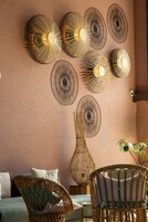 Quarto com ventilador fixado na parede, cadeira de fibra e sofá com almofadas.