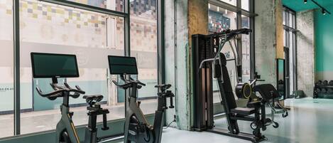 Uma academia com bicicletas ergométricas, uma máquina de musculação e esteira.
