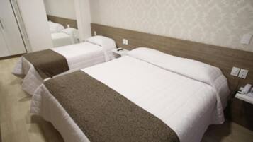 Quarto de hotel com duas camas, cabeceira de madeira, carpete estampado e parede branca com um design discreto.