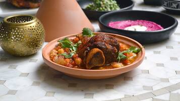 Um prato marroquino tradicional de tajine com carne e legumes, servido em um prato de barro.