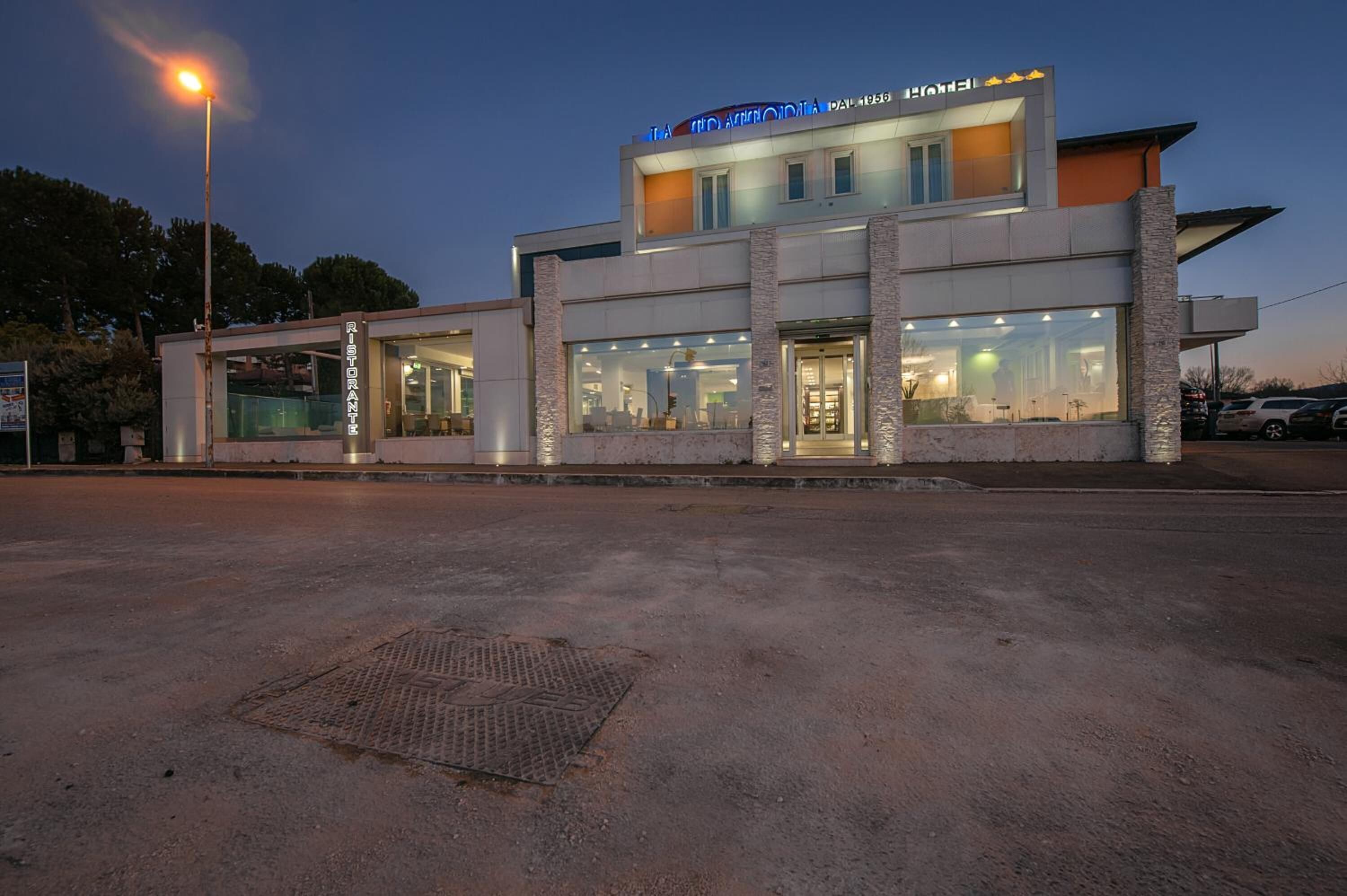 Um hotel moderno com fachada de vidro, entrada visível e uma placa indicando que é um hotel.