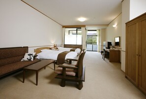 Quarto de hotel com cama, sofá, escrivaninha e guarda-roupa.
